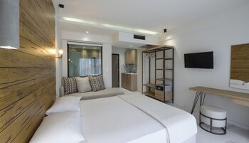 Quarto de hotel moderno com uma cama grande, uma escrivaninha e uma televisão.