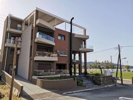 Um edifício de vários andares com telhado plano, varandas e uma placa com a inscrição 'THETIS'.