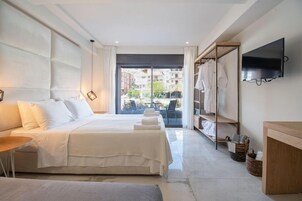 Quarto de hotel moderno com uma cama grande, televisão na parede e vista da cidade pela janela.