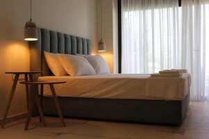 Quarto moderno com cama, mesas de cabeceira e janela com cortinas.