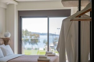 Quarto com uma janela grande, uma cama, toalha pendurada e vista para um corpo d'água.