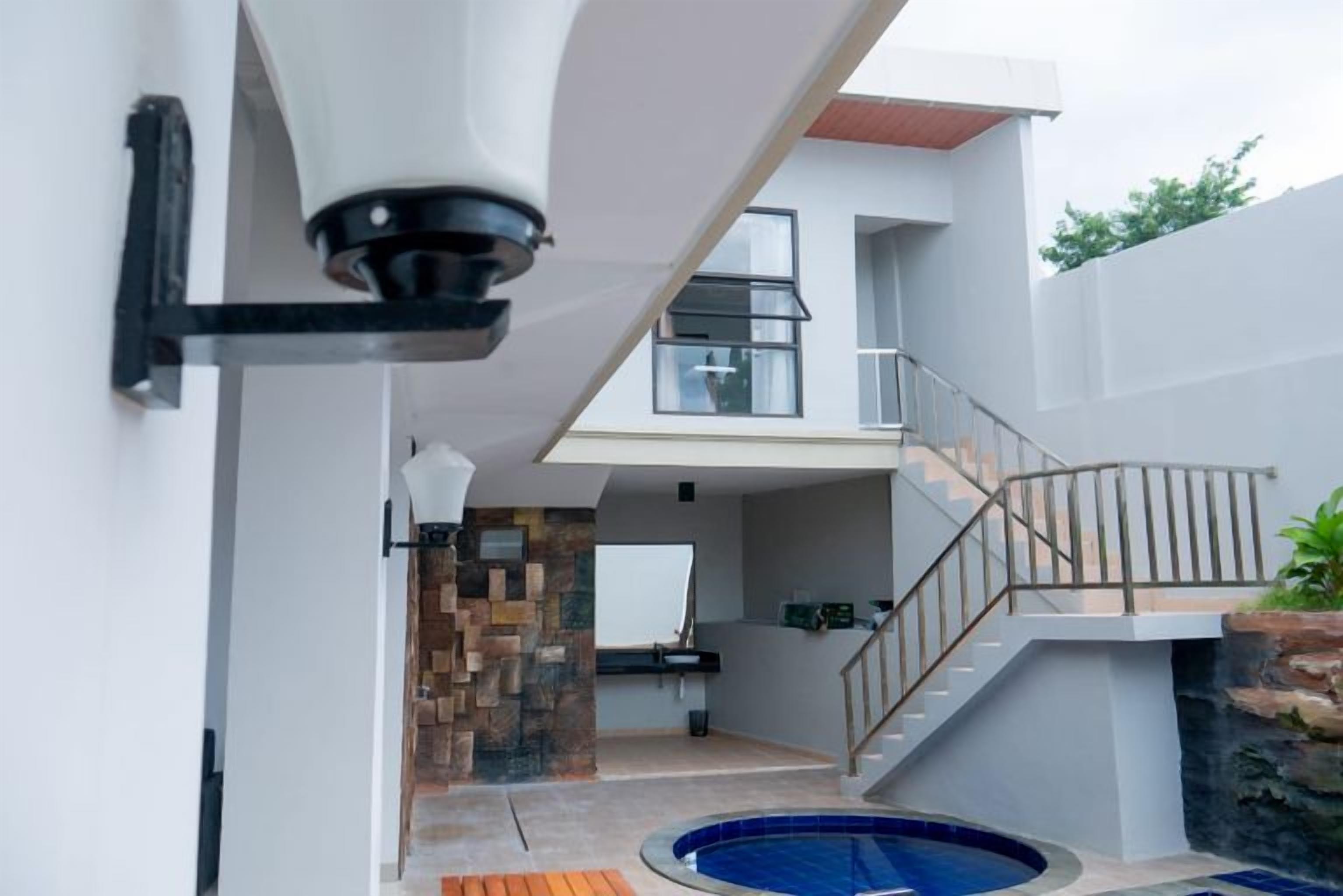Uma casa moderna com piscina, escadaria e muro de pedra.