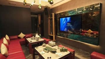 Uma sala moderna com um sofá vermelho, uma mesa de jantar com jogos de chá e uma grande tela de televisão.