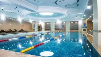 Piscina interna com divisórias de pista, piso azulejado e teto com luminárias circulares.