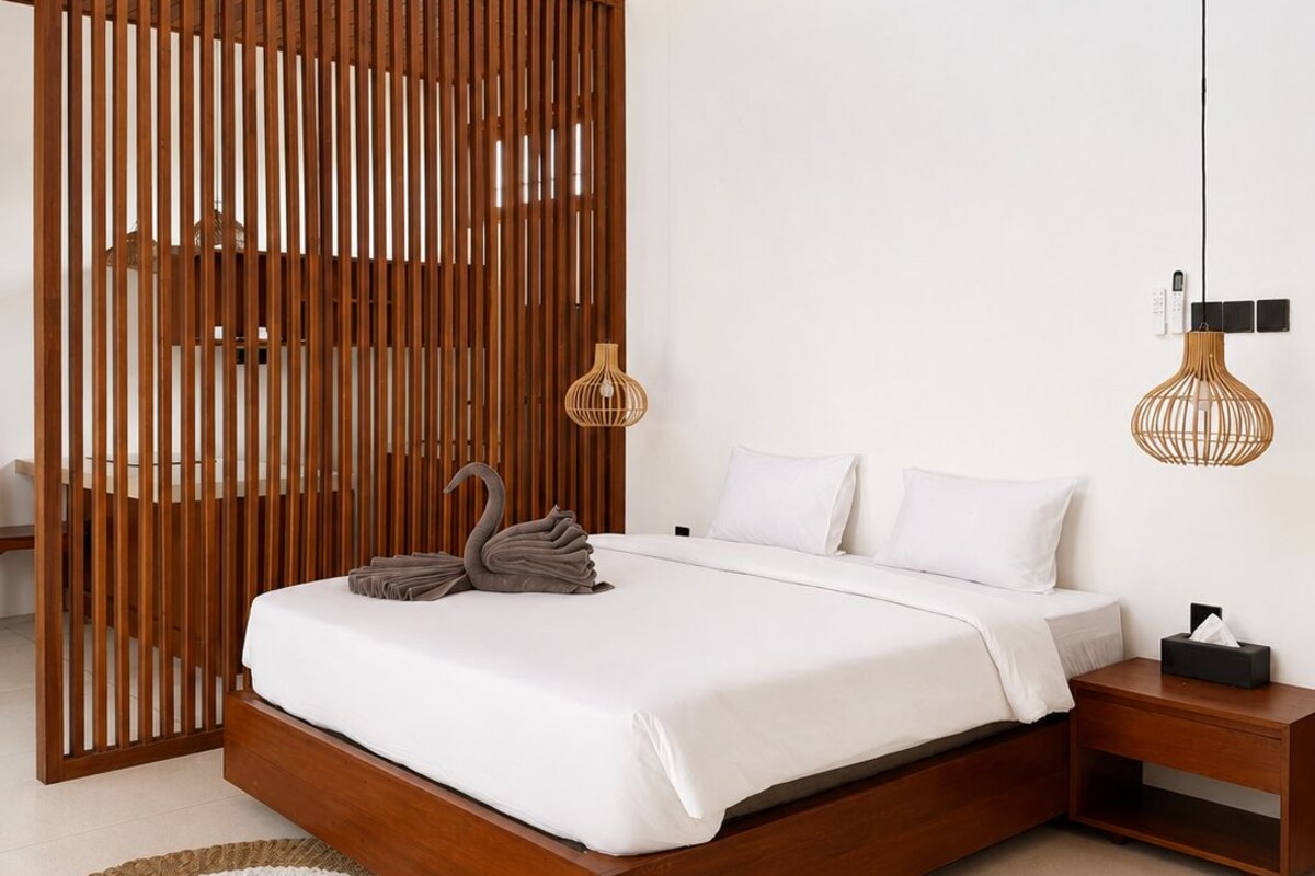 Quarto moderno com estrutura de cama de madeira, tapete redondo tecido e divisória de madeira.