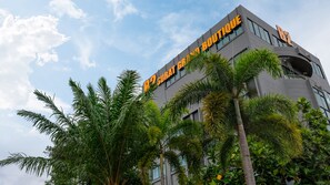 Um edifício com uma placa indicando 'R2 Surat Boutique' e cercado por palmeiras.