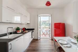 Cozinha moderna com armários brancos, bancada preta e geladeira vermelha.