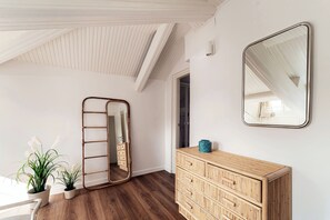 Quarto com guarda-roupa de madeira, espelho e escada.