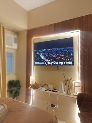 Quarto de hotel com uma grande TV de tela plana na parede exibindo uma vista urbana.