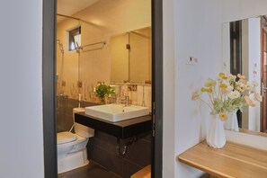 Uma casa de banho moderna com chuveiro, sanita e lavatório.