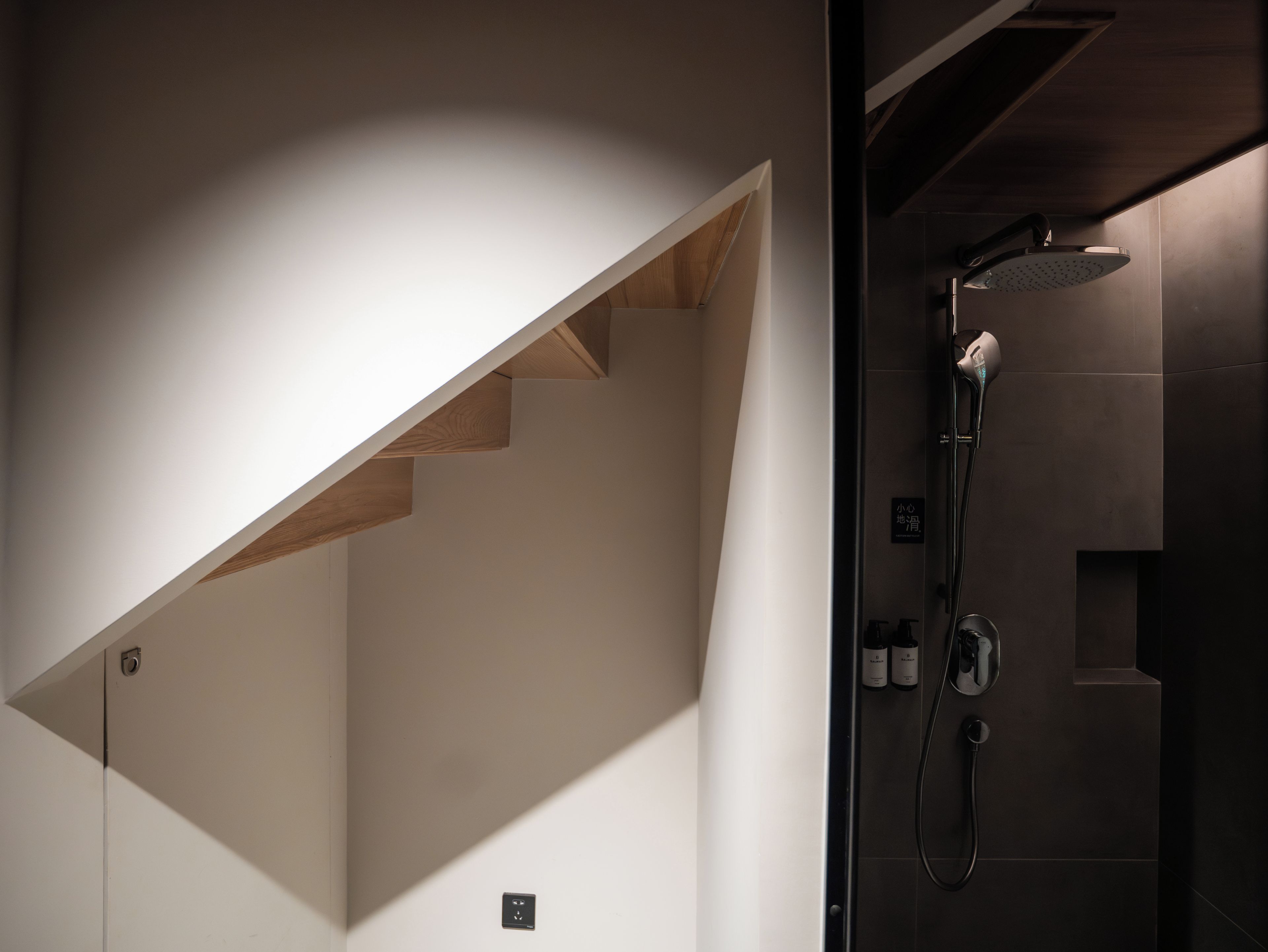 Casa de banho moderna com chuveiro, escada e painel de comando fixado na parede.