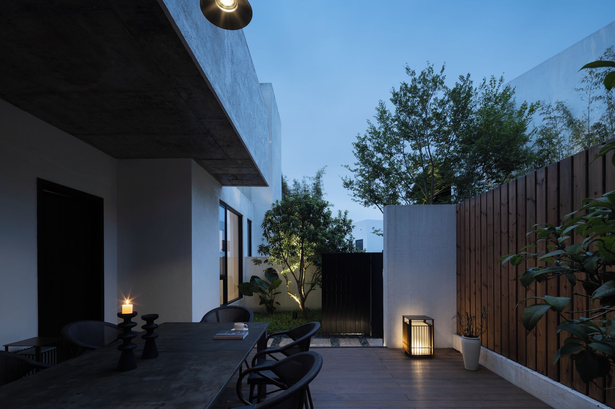 Área de pátio externo com mesa, cadeiras e uma vela.