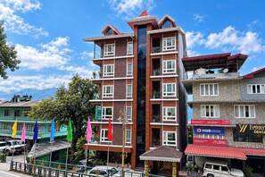 Um hotel de vários andares com uma torre central, varandas e telhado vermelho.