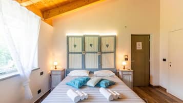 Quarto de hotel com cama, luminárias de cabeceira, porta e janela com cortinas.