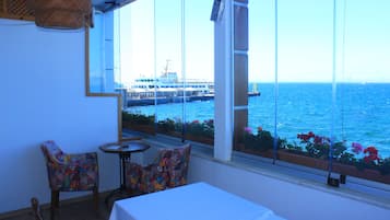 Varanda com mesa e duas cadeiras, vista para a água e um cais.