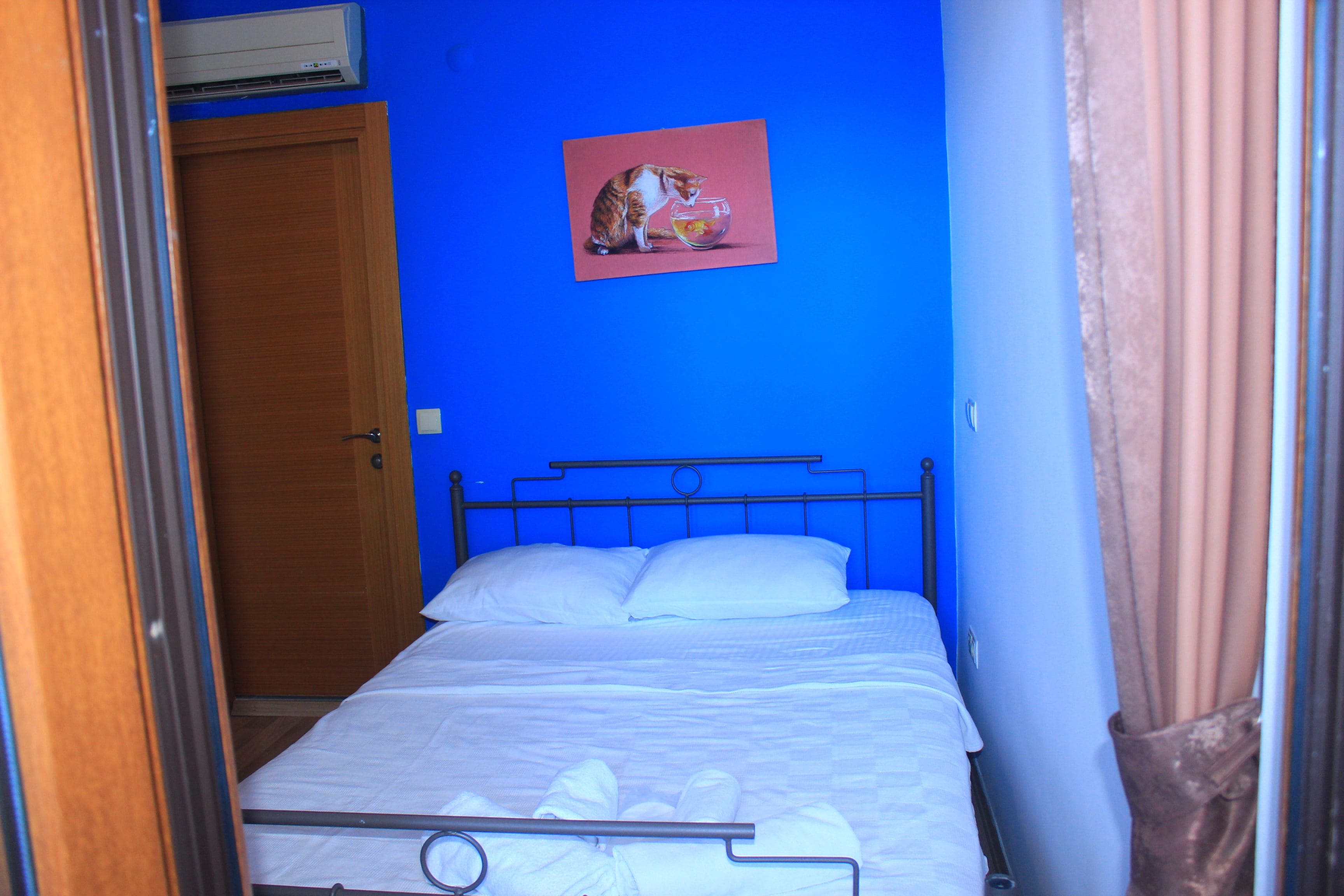 Uma cama de solteiro com roupa de cama branca num quarto com paredes azuis.