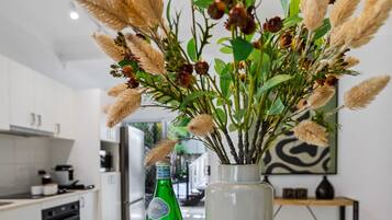 Uma bancada de cozinha com uma garrafa de água Pellegrino, dois copos e um vaso com flores secas.