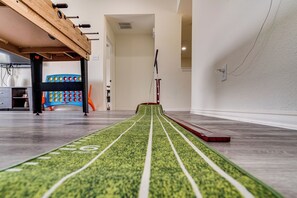 Corredor com pista de atletismo verde, teto de madeira e parede branca.