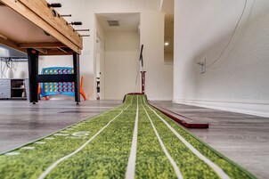 Corredor com pista de atletismo verde, teto de madeira e parede branca.