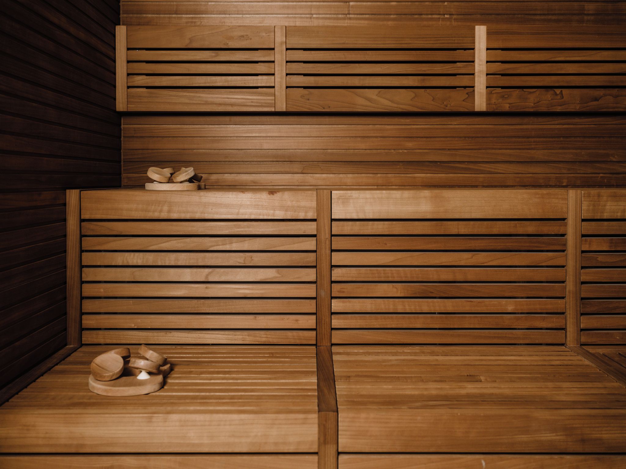 Uma sauna com bancos de madeira e um banco com toalha e uma garrafa.