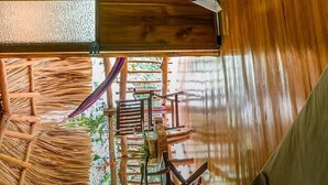 Quarto com piso de madeira, janela com vidro fosco e cama com manta estampada.