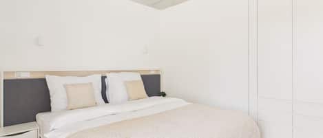 Quarto com cama, mesa de cabeceira e criado-mudo.