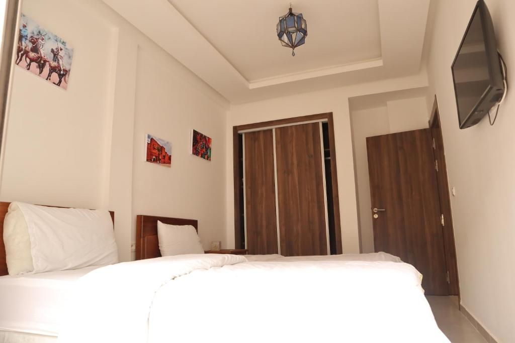 Quarto com cama, guarda-roupa, televisão e obras de arte nas paredes.