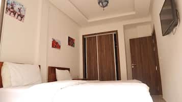 Quarto com cama, guarda-roupa, televisão e obras de arte nas paredes.