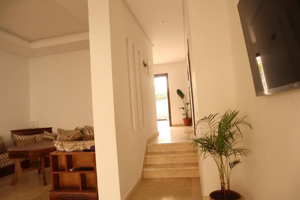 Uma sala de estar com sofá, mesa de centro e escada que dá para outro cômodo.