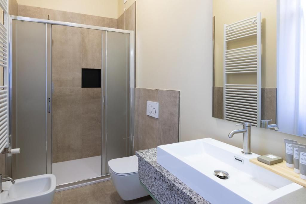 Casa de banho moderna com cabine de duche em vidro, lavatório branco com bancada de granito e espelho com porta-toalhas.