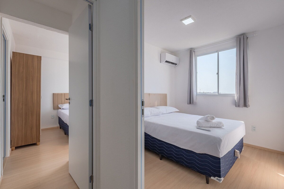 Quarto de hotel com cama, janela e ar condicionado.