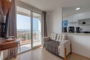 Uma sala de estar moderna com sofá, mesa de centro e vista para uma varanda.