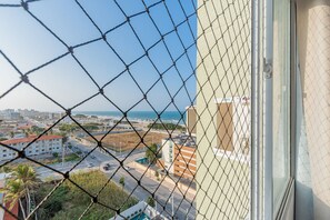 Cerca de arame com vista para um horizonte costeiro, prédios e céu claro.