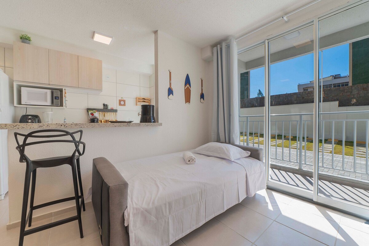 Quarto compacto com cama, cozinha compacta e varanda com vista.