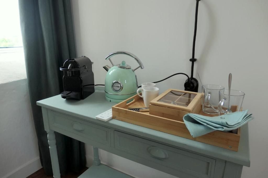 Uma cozinha compacta com cafeteira, chaleira e um jogo de chá e copos.