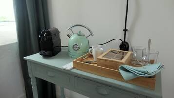 Uma cozinha compacta com cafeteira, chaleira e um jogo de chá e copos.