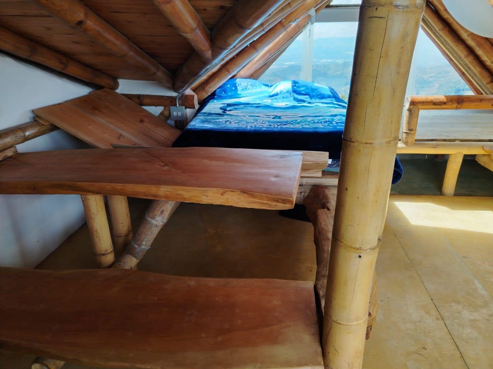Interior de madeira com uma cama, uma mesa e vista pela janela.
