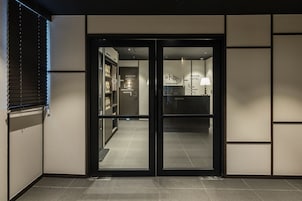 Entrada de hotel com balcão de recepção e porta de vidro.