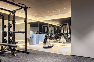 Academia com equipamentos de musculação, colchonetes de yoga e espelho.