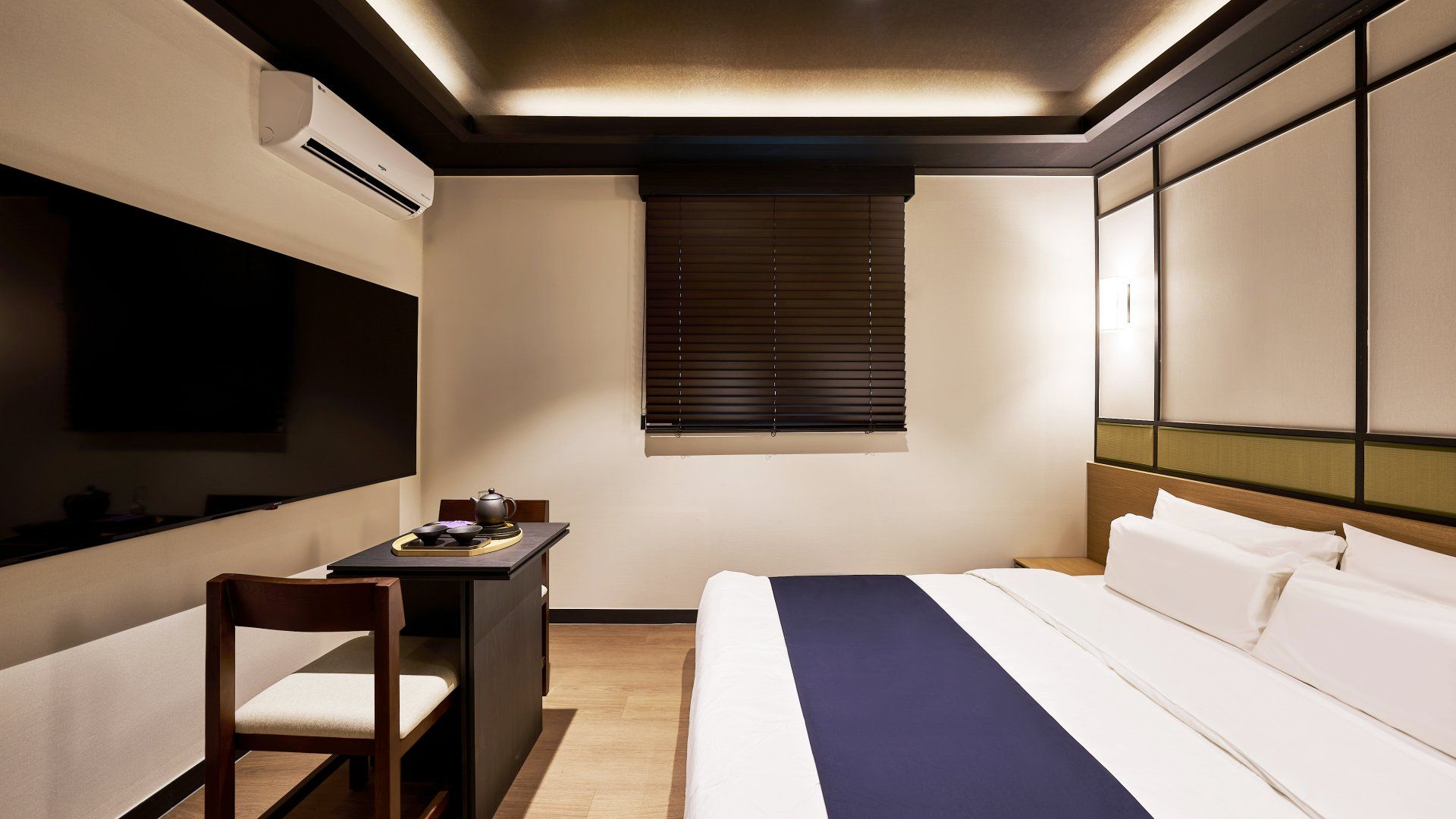 Quarto de hotel com cama, escrivaninha e cadeira.