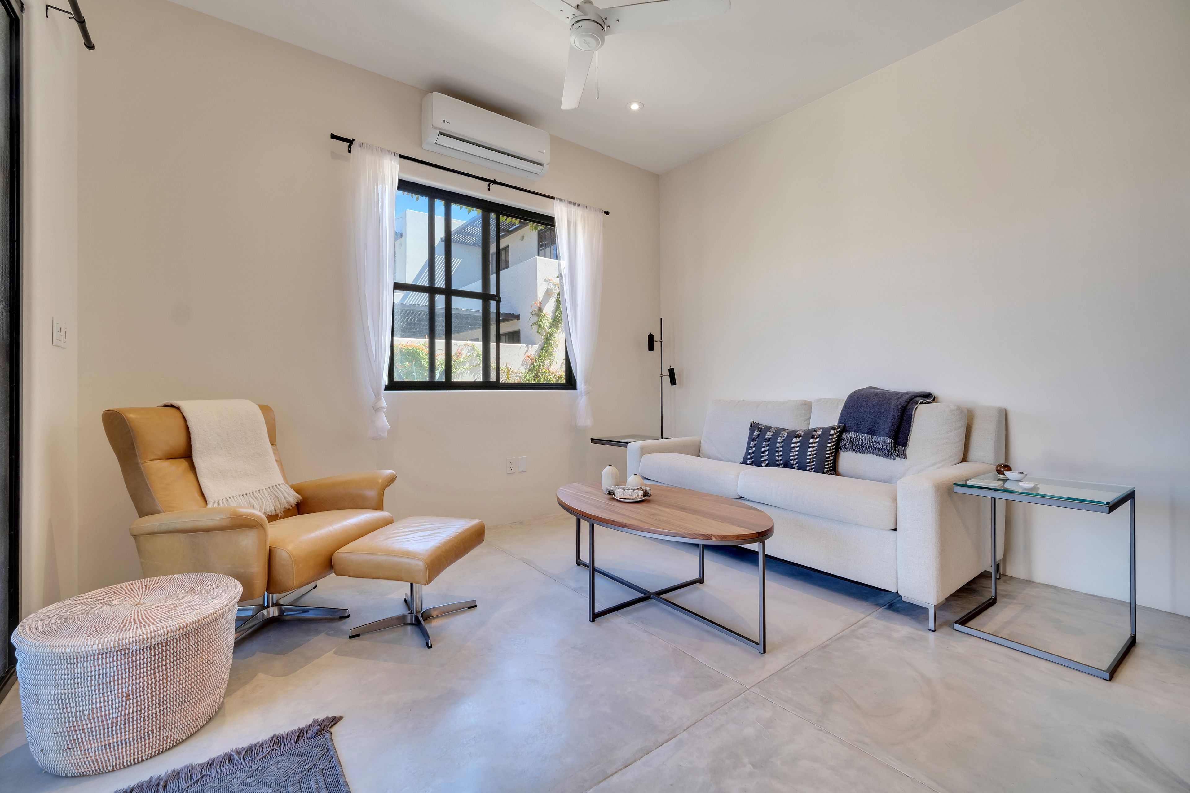 Uma sala de estar moderna com sofá, poltrona, banqueta e mesa de centro.