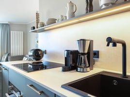 Cozinha moderna com fogão embutido, cafeteira e pia.