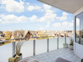 Varanda com vista para edifícios residenciais, guarda-corpo e plantas em vasos.