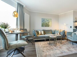 Uma sala de estar moderna com sofá, poltronas, mesa de jantar e mesa de centro.