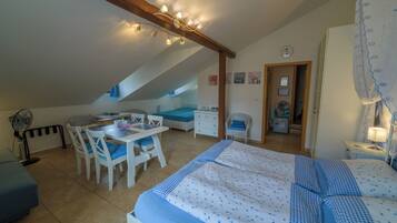 Quarto com cama, mesa, cadeiras, ventoinha e janela.
