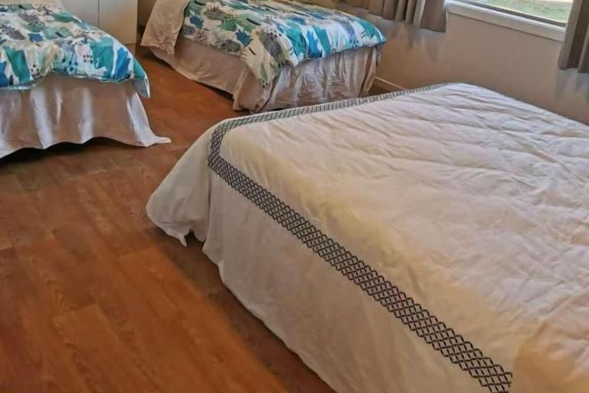Quarto com duas camas, um guarda-roupa e uma janela com cortinas.