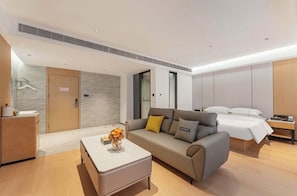 Quarto de hotel moderno com cama, sofá, mesa de centro e escrivaninha.