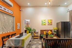 Cozinha moderna com área de refeições, incluindo geladeira, mesa com cadeiras e luminária pendente.