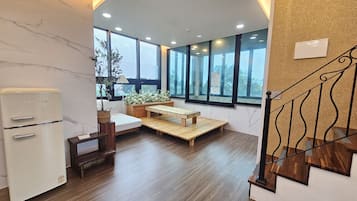 Cozinha moderna com geladeira embutida, piso de madeira e janelas amplas que oferecem vista para o exterior.