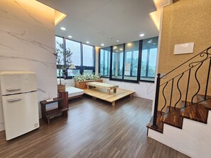Cozinha moderna com geladeira embutida, piso de madeira e janelas amplas que oferecem vista para o exterior.